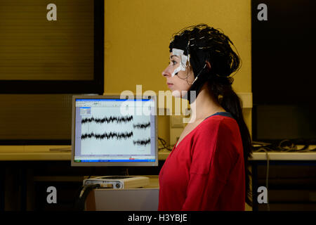 Person undergoing an electroencephalogram with an EEG cap to scan her ...