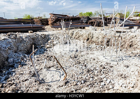 construction rebar protruding out of the ground against a cloudy blue ...