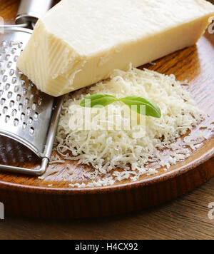 whole and grated parmesan cheese on wooden cutting board Stock Photo ...