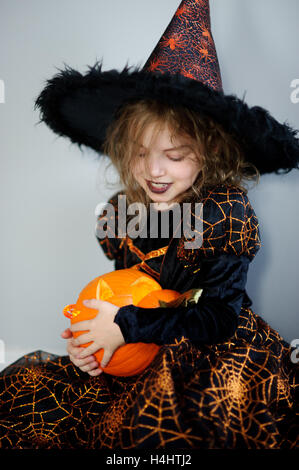 Image of evil witch girl in black halloween costume holding carved ...