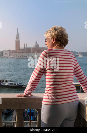 Woman standing on balcony, looking at ornate architecture, Porto ...