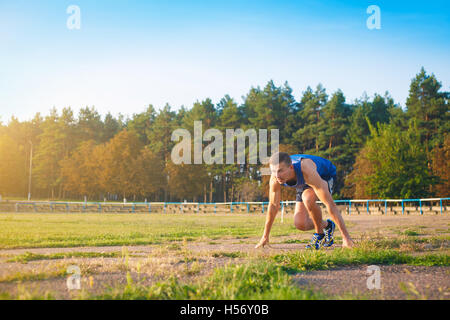 Man in low start position on old stadium. Athlete in starting position ...