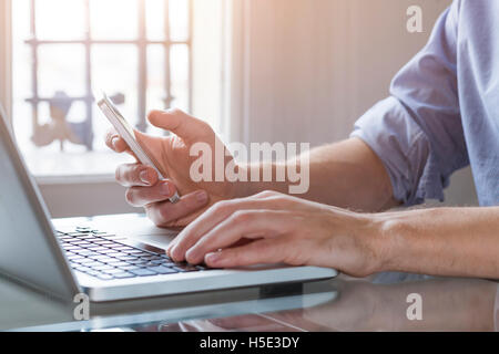 Young freelancer with mobile phone and laptop at home Stock Photo - Alamy