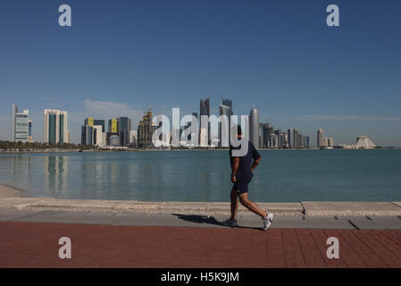 Man jogging along the Corniche with West Bay skyline of Doha in the ...