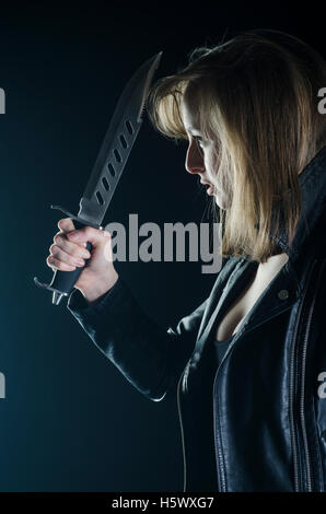 Blonde female holding a dagger in the dark Stock Photo - Alamy