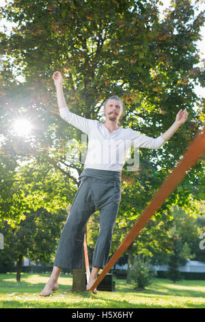 Portrait of man balancing a tightrope or slackline in park environment ...