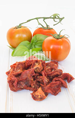 tomatoes with green basil leaves and dry pepper on a white background ...