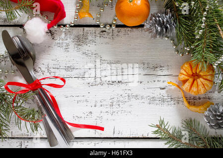 Christmas tree branch, ornaments and cutlery on a white wooden table ...