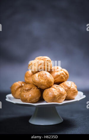 Profiterole eclair stack on platter topped with melted chocolate Stock ...