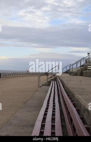 Benches on a promenade by the sea on a cloudy day at dusk Stock Photo ...