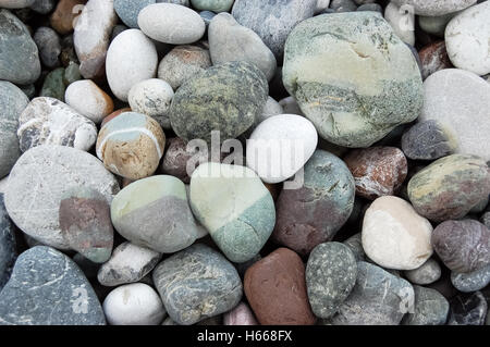 Beach of multi-colored round pebbles, foam and splash of salty waves ...
