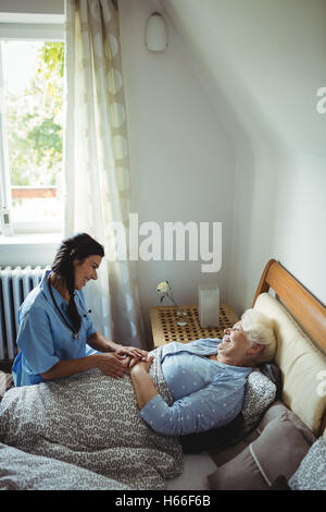 Nurse interacting with senior woman on bed Stock Photo - Alamy