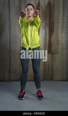 Deep squat. Front view of young beautiful woman in sportswear doing ...