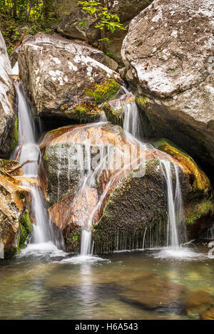 Fresh water mountain stream cascades over smooth boulders and mossy ...