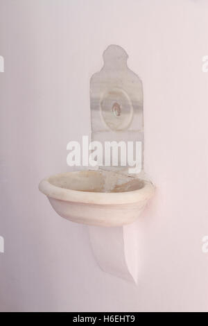 holy water in an old stoup made of copper with verdigris in the inside ...