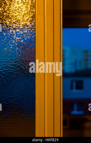 Tungsten lighting reflecting off a bumpy window, with another window in ...