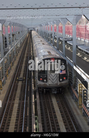the J Train along with cars and pedestrians travels over the ...