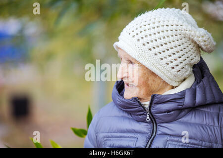 Elderly woman in autumn park doing warm up before nordic walking among ...