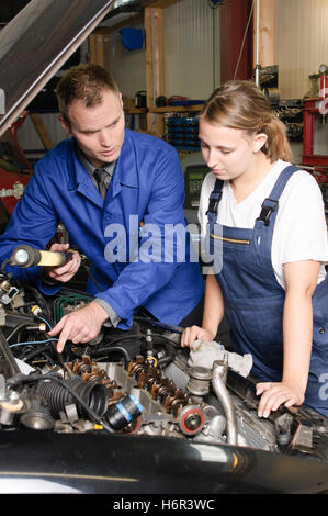 mechanic with female apprentice by car with bonnet raised Stock Photo ...