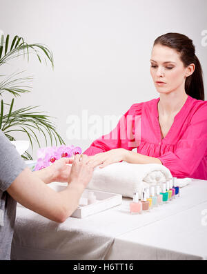 Pretty young woman doing nails displaying her workplace in nail salon ...