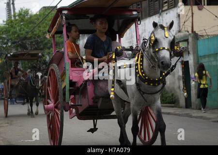 A horse drawn carriage known as a Kalesa being driven in downtown Cebu ...