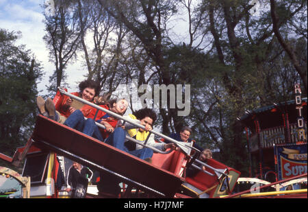 Twist ride passengers at amusement park fairground riders or travelling ...