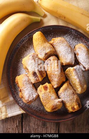 Fried bananas in batter on a plate closeup on the table. horizontal ...