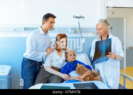 Pediatrician visiting parents and child in hospital bed ward, doctor ...