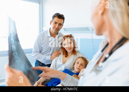 Pediatrician visiting parents and child in hospital bed ward, doctor ...