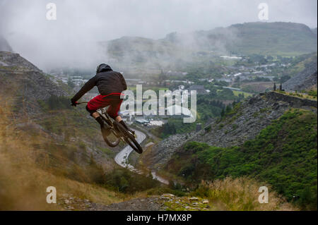 A mountain biker jumps a rock drop at Antur Stiniog mountain bike ...