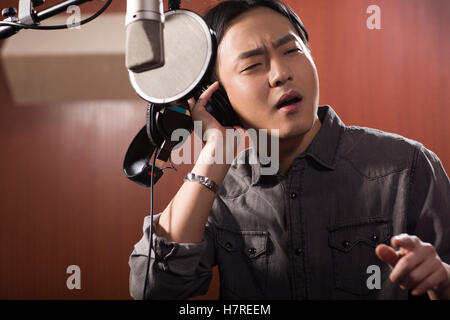 Young Chinese man singing in recording studio Stock Photo - Alamy