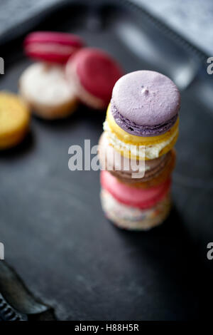 stack of baked round yellow lemon macarons on a blue-pink background ...