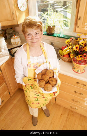 Smiling senior woman offering muffins Stock Photo - Alamy