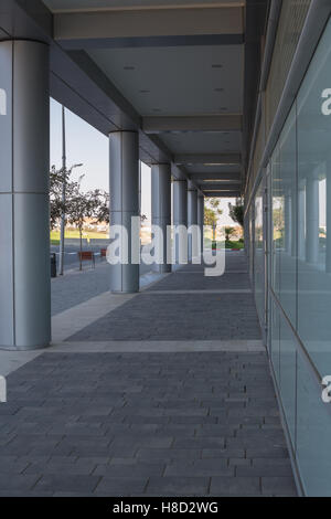 The entrance of a modern building with large columns is illuminated at ...
