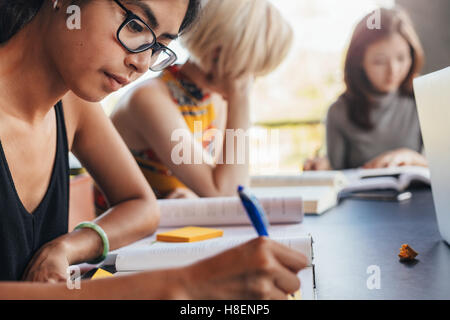 Young Asian women writing notes in notebook using laptop computer ...