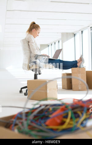 Businesswoman using laptop with feet on cardboard boxes Stock Photo - Alamy