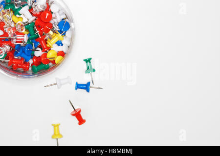 Top view of multicolored push pins in a plastic box on a concrete floor ...