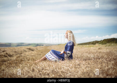 Blonde woman sitting in field Stock Photo - Alamy