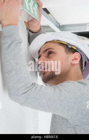 man fixing exit sign to wall Stock Photo - Alamy