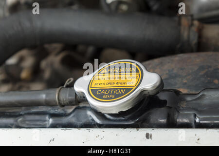 Radiator cap with bilingual warning text on its label. It says to never ...