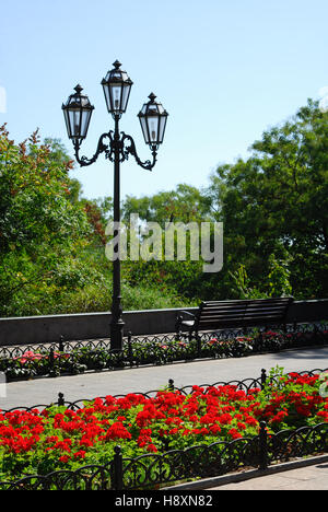 Cast iron lamp post with three globes, on bridge parapet over river ...