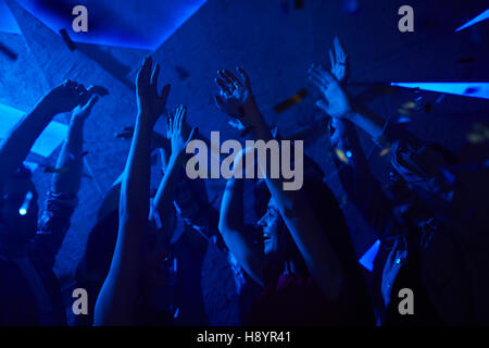 Ecstatic friends with raised hands dancing at party Stock Photo - Alamy