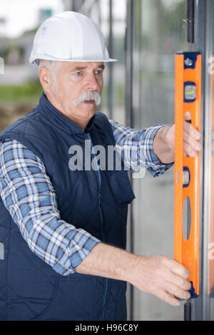 Man using a spirit level to plumb a wall. Home renovation concept ...