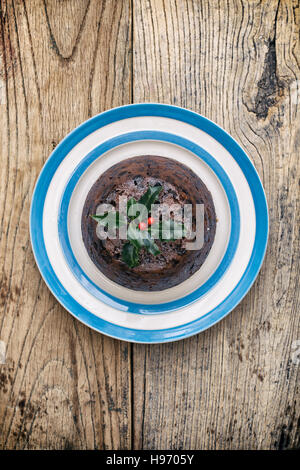 Traditional Christmas pudding with a sprig of holly and brandy butter ...