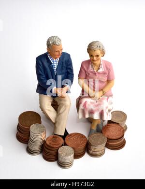 A miniature figurine senior elderly couple sitting amongst some coins ...