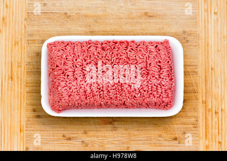 Raw ground meat centered on wooden cutting board surrounded by cherry ...