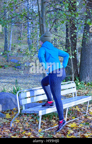 Woman exercising and stretching by plants at park Stock Photo - Alamy