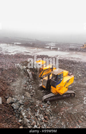 A Broyt tracked loader dumps a bucket of rocks in a quarry in heavy ...
