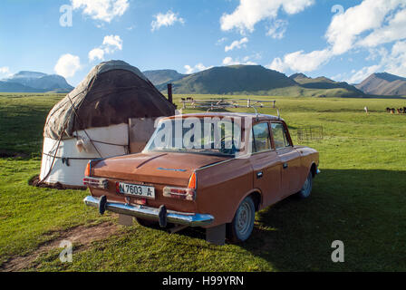 An old car sits outside a camp of yurts in the jailoo, or summer ...