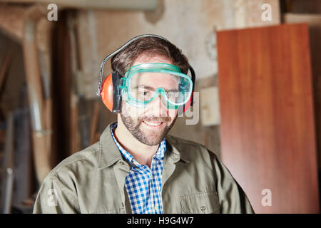 Craftsman with protective goggles, ear protection, face mask and helmet ...